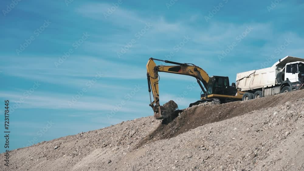 Excavator working on earthmoving at open pit mining, loading the truck ...
