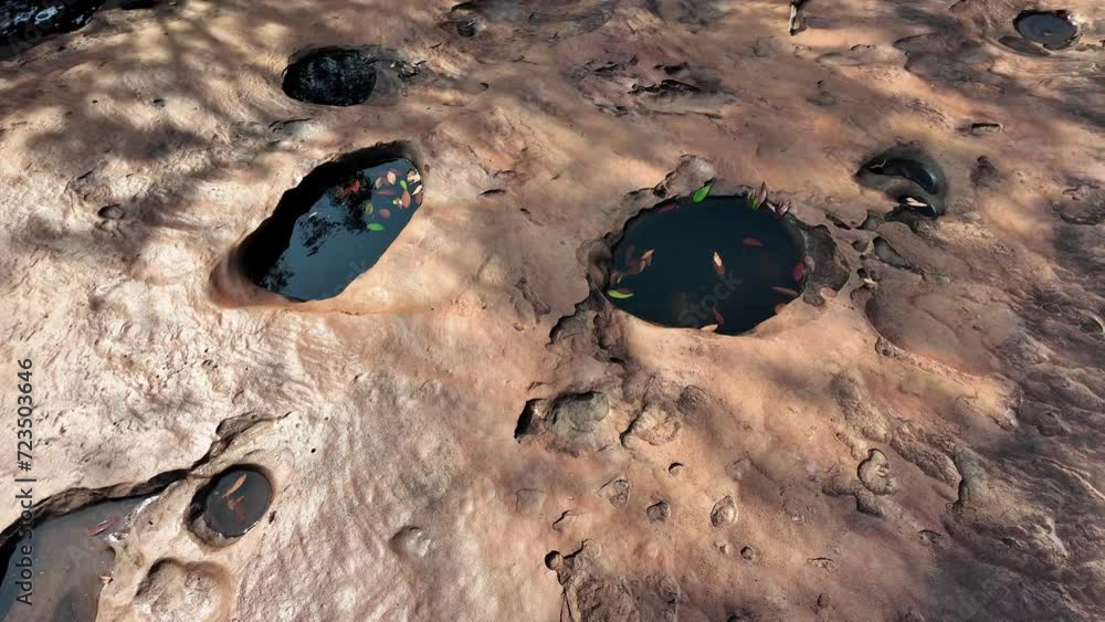 Rocky terrain with natural potholes filled with water and scattered ...