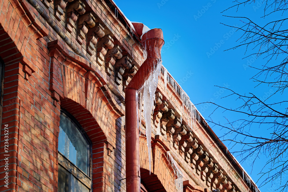 Ice dams, huge icicles hanging on gutter on facade of historic building ...