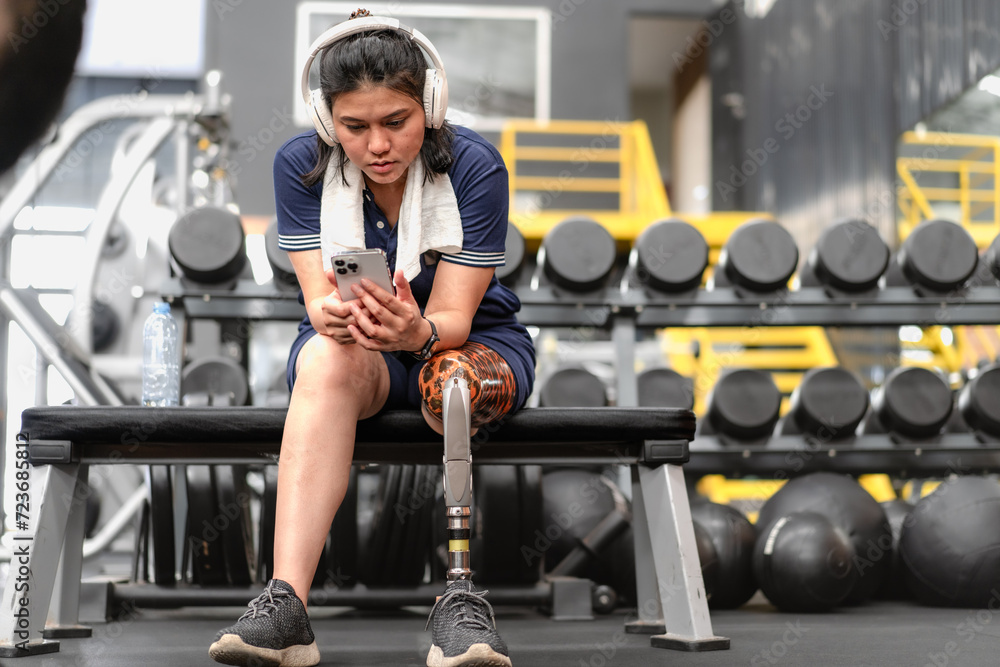 Prosthetic leg woman sits relaxing in gym. Asian female with foot ...