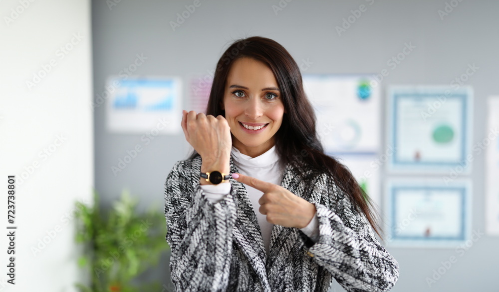 Foto de Smiling business woman pretty shows on watch. Woman achieves ...