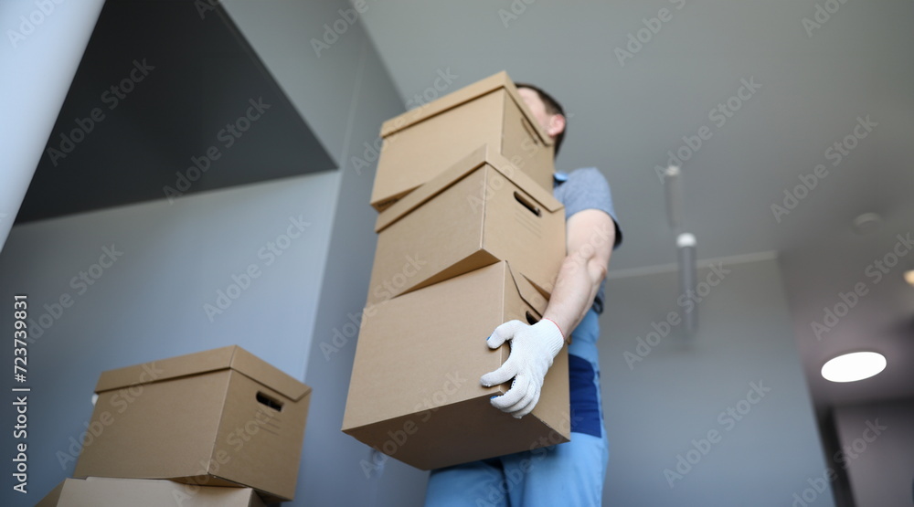 Man in work clothes and gloves carries cardboard boxes. Folding boxes ...