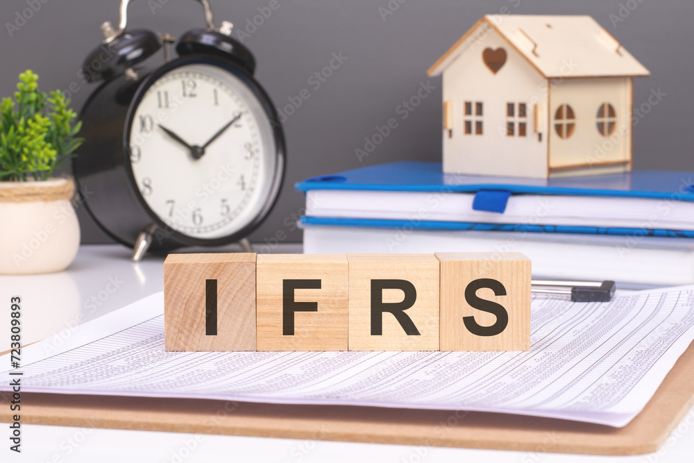 ifrs word in wooden blocks with small wooden house and alarm clock on ...