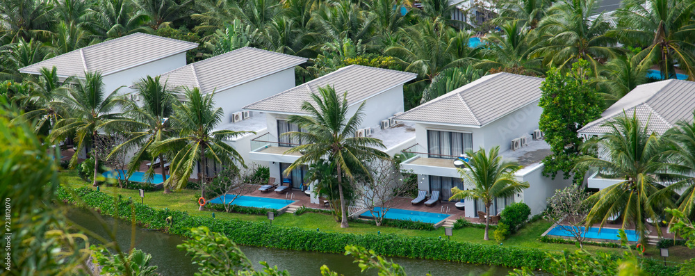 Panorama aerial riverside white painted tropical villas, swimming pool ...