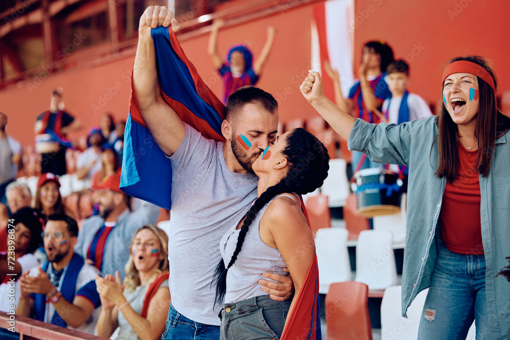 Couple of sports fans kissing while celebrating during match at stadium ...