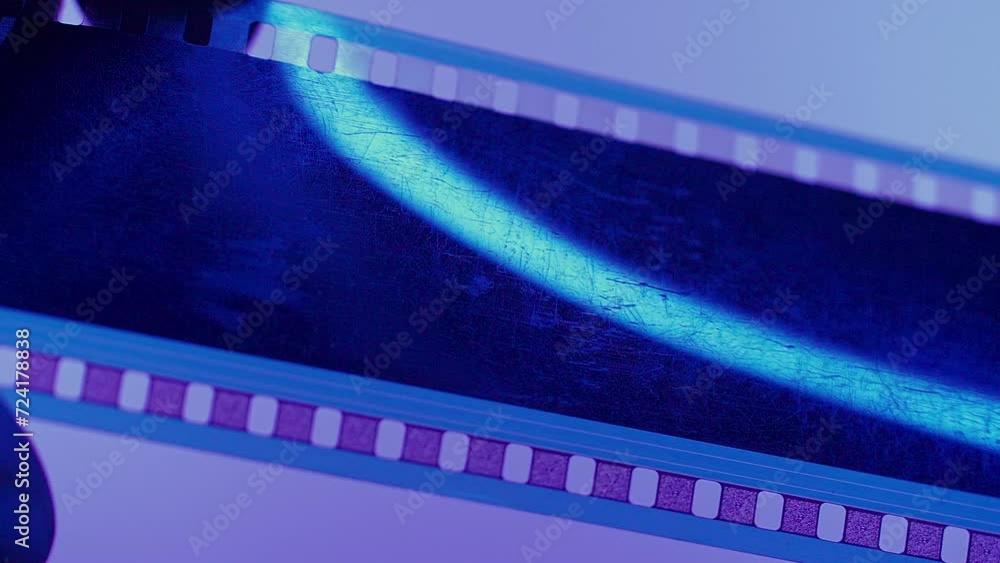 Scratched texture of old film in darkness in blue neon light close up ...
