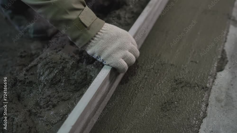 A builder uses a trowel to level a cement mortar screed. Concrete work ...