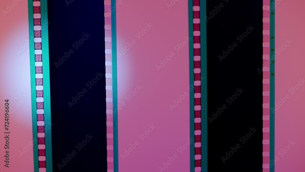 Two vertical film strips on a pink background with white circular light ...