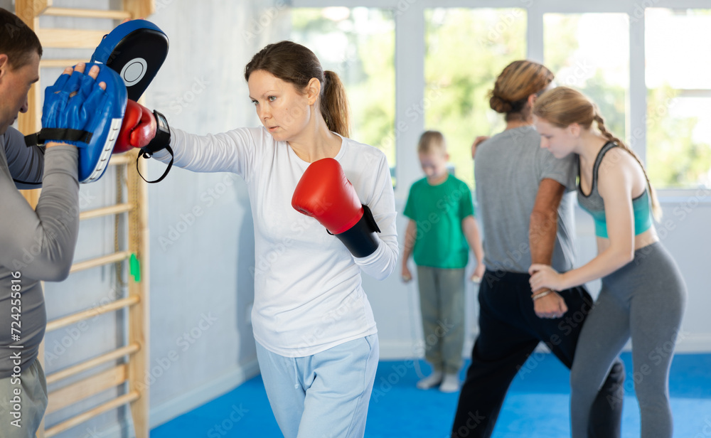 Woman works out strength and speed of boxing punch mitts with help of ...