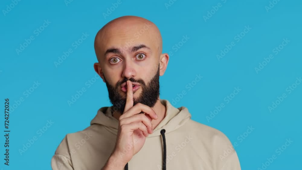 Middle eastern man doing hush silence symbol in studio, asking to keep ...
