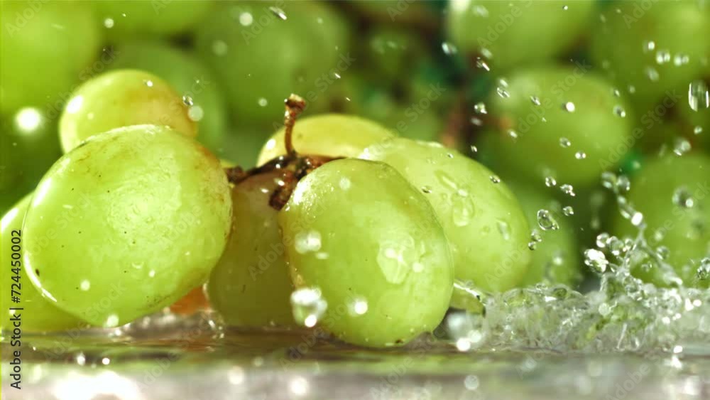 Raindrops fall on green grapes. Filmed on a high-speed camera at 1000 ...