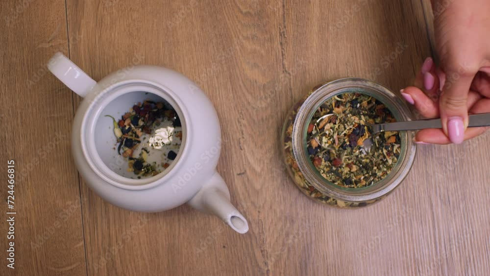 Conceptual shot from above of how hands add tea leaves to a teapot, a ...