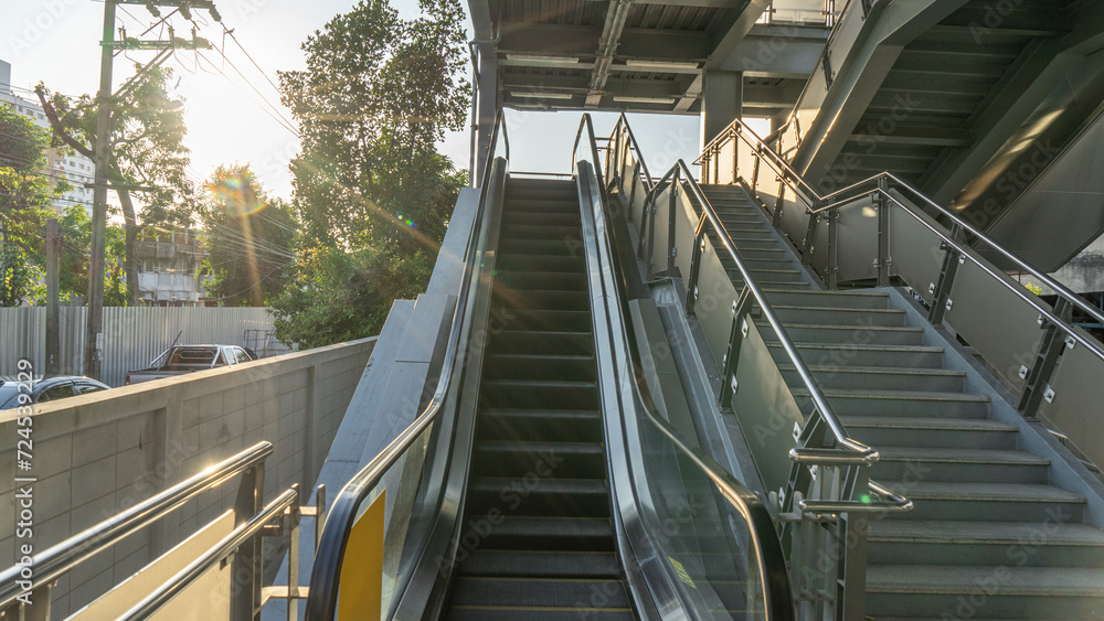 Photograph of an urban location, an escalator flanked by cement stairs ...