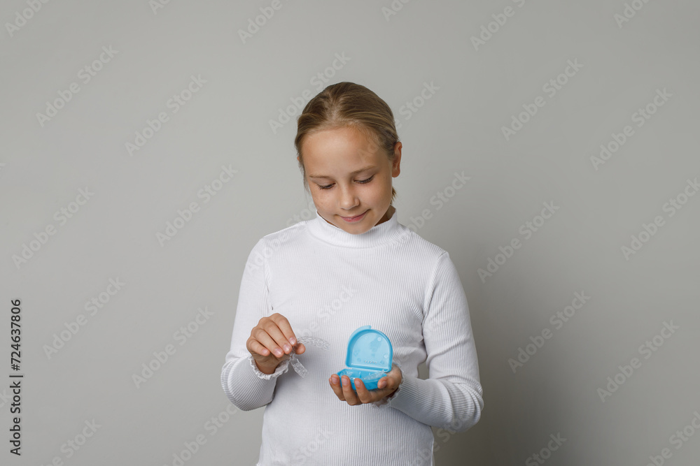Cute child girl wearing white t-shirt holding an invisible aligner ...