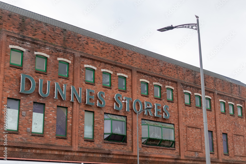 Old brick Dunnes Stores building on River Lee embankment against blue ...
