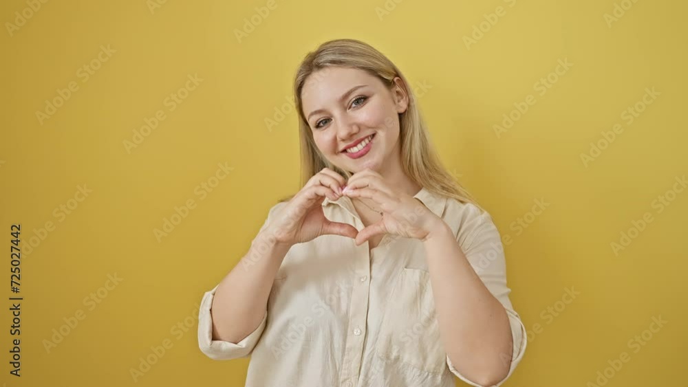 Smitten blonde young woman making romantic heart shape hand symbol ...