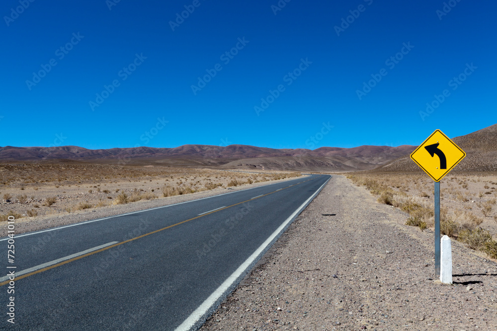 Yellow road sign with a black arrow pointing to the left (road goes to ...