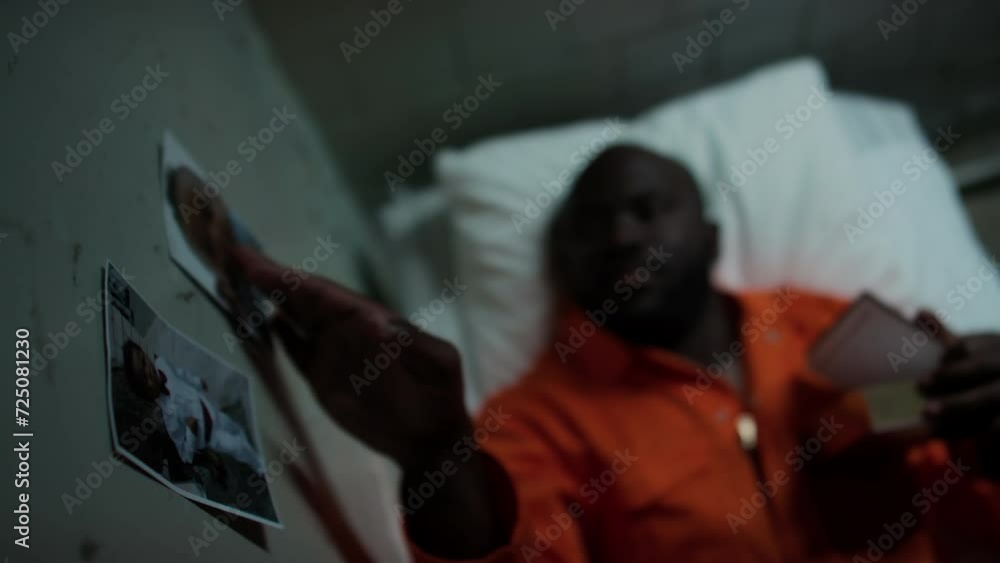 High angle view of Black inmate resting on bed in prison cell, reading ...