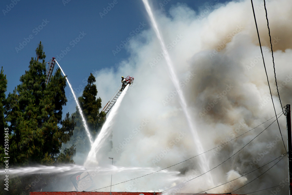 Firemen attacking a fire with water canon from the top of a hook and ...