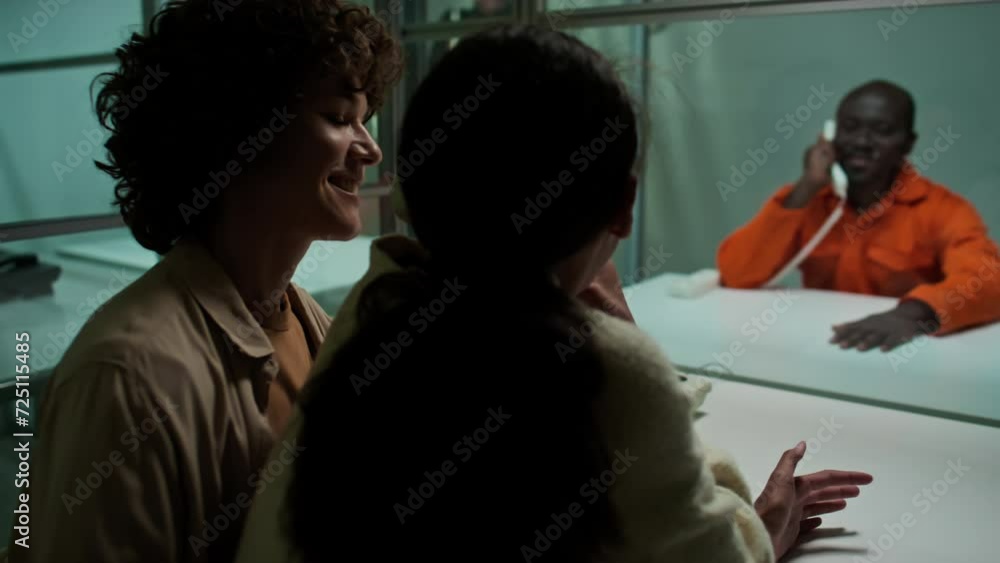 Rack focus shot of Black inmate sitting behind glass wall and having ...