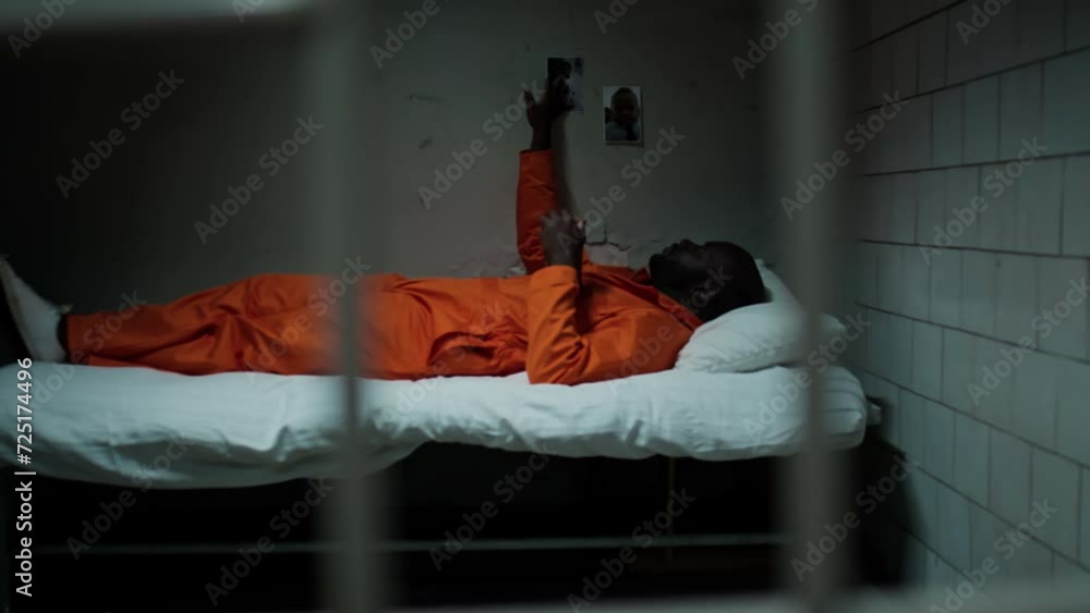 Vidéo Stock View through bars of African American inmate in orange ...