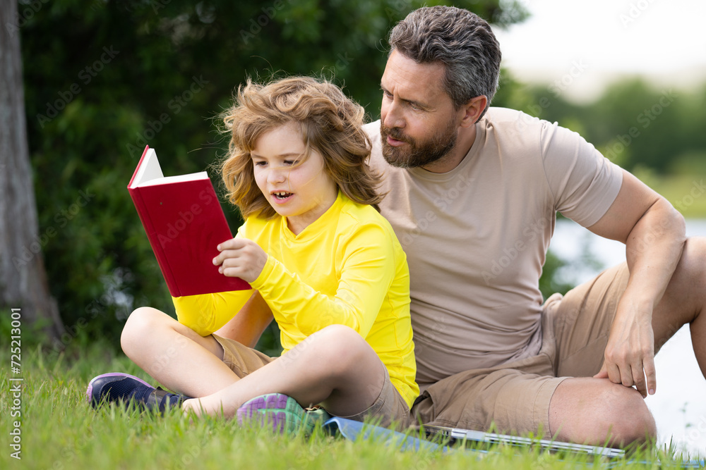 Father read a book with son in a park outdoors. Father and child son ...
