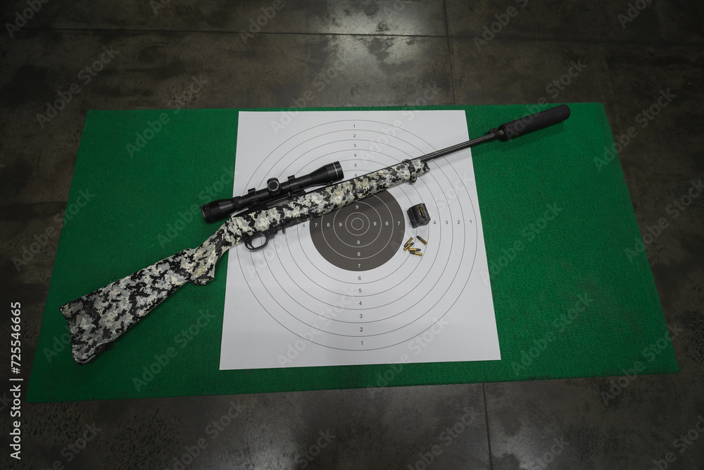 A shooting target and a small caliber rifle with an optical sight in a ...