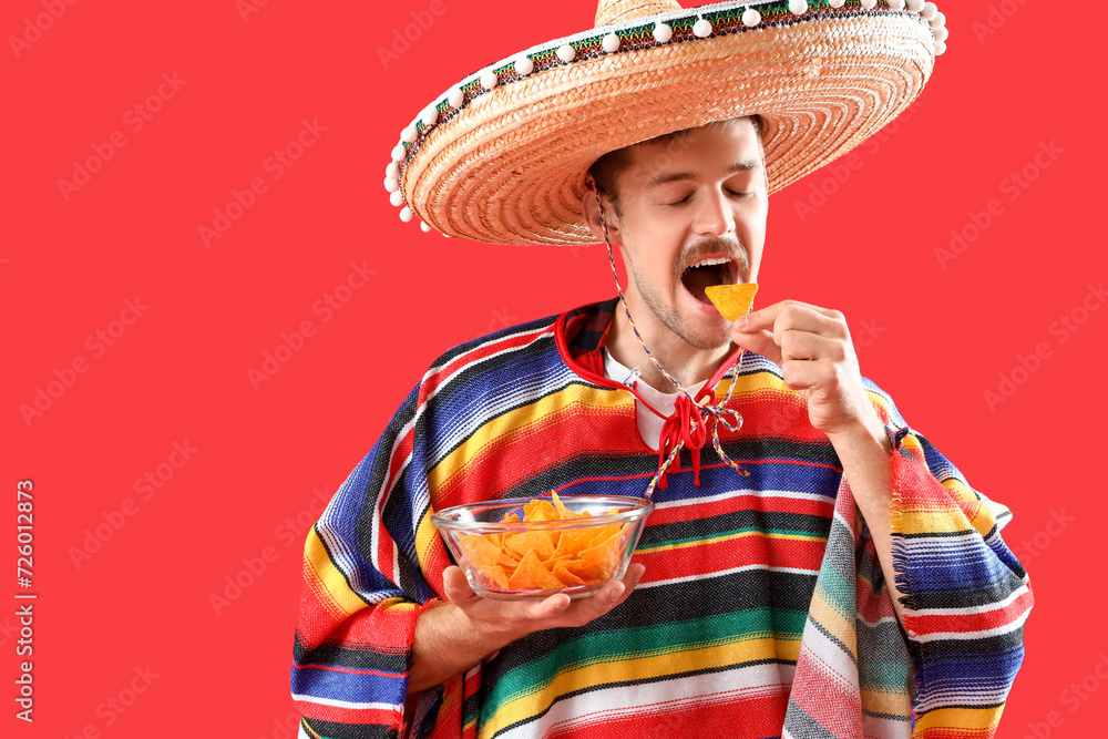 Young Mexican man eating nachos on red background Stock 写真 | Adobe Stock