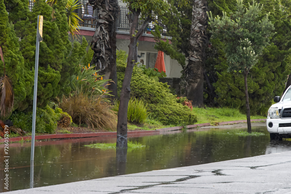 Sidewalk and side of road with standing water, flooded after heavy rain ...