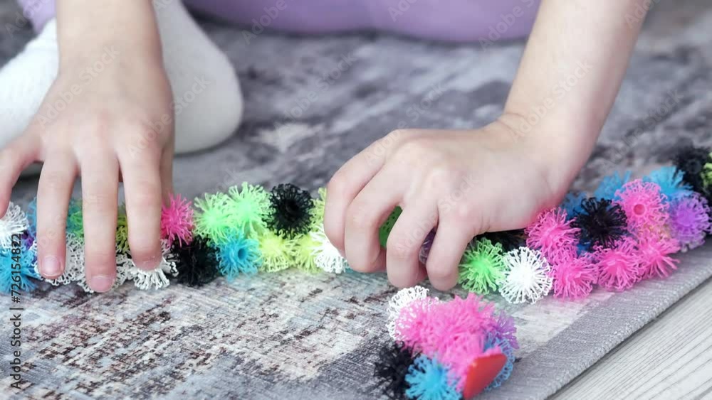 Close-up of a child assembling a snake from individual elements shaped ...