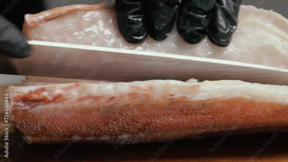 The chef is cutting raw fish. He cuts the meat off the bones and ...