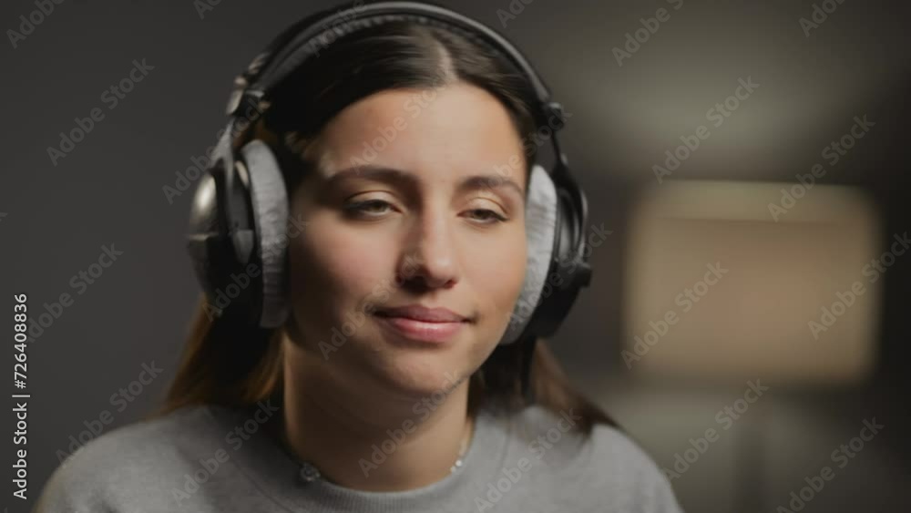 Girl sitting with headphones on at her laptop. Girl listening to music ...