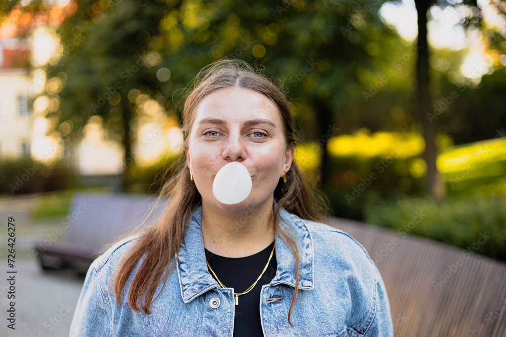 Portrait of young playful hipster female in the park.. Model blowing ...