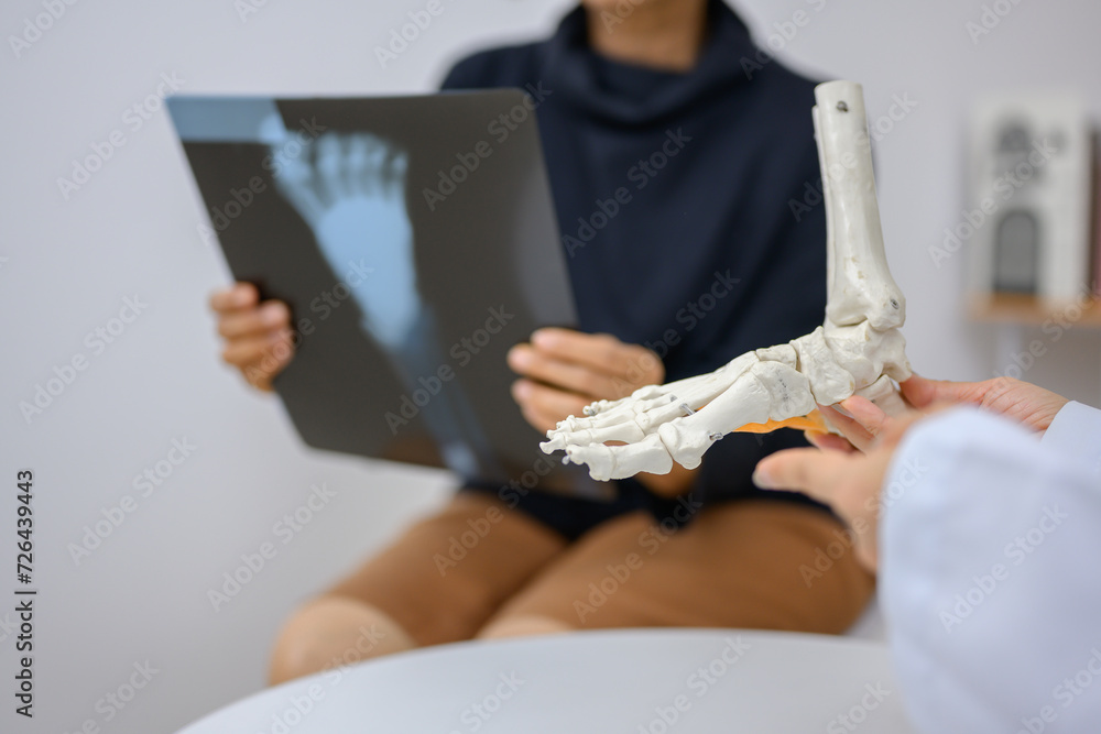 An orthopedic doctor holding a model of ankle and foot bones is ...