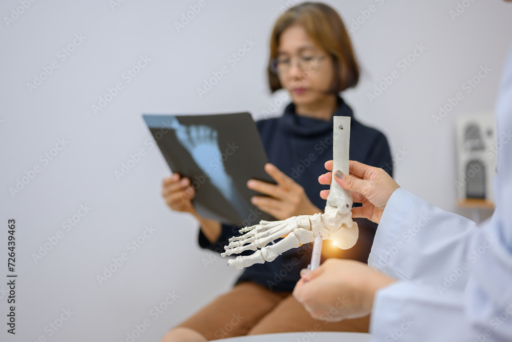 Asian female orthopedist Pointing to the ankle and foot bone model is ...