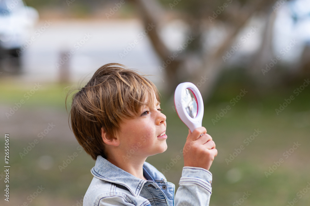 head and shoulders of curious child looking through magnifying glass ...