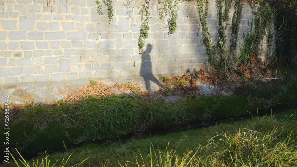Shadow of a young passerby on an old stone wall. Shadow silhouette of a ...