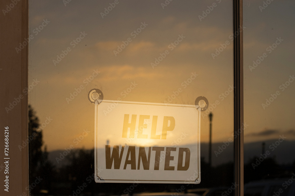 Help Wanted signage in the storefront window during sunset. America's ...