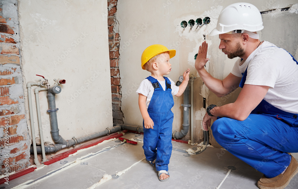 Male worker and little boy slapping hands giving high five in apartment ...