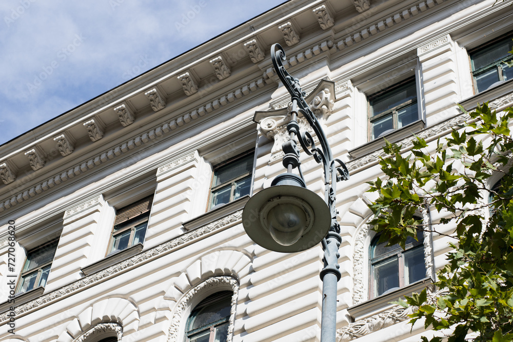City lantern of unusual antique shape. A tall white building and a ...