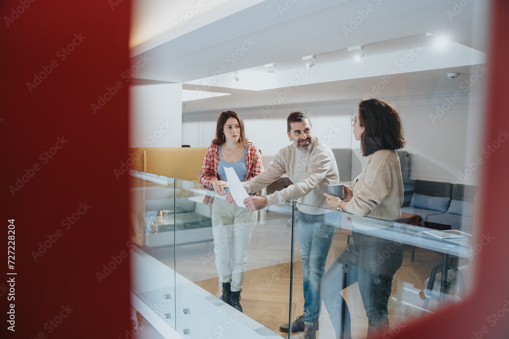 Three colleagues engage in a casual conversation at a brightly lit ...