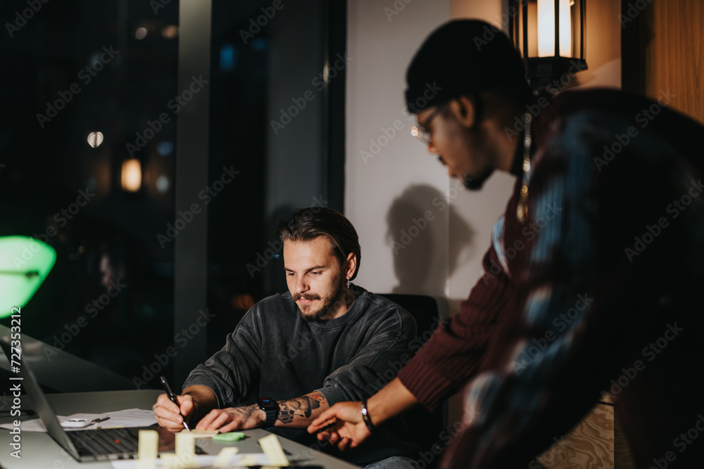 Two multigenerational male colleagues collaborate after hours, focusing ...