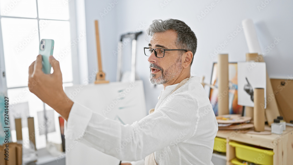 Handsome young hispanic, grey-haired male artist engrossed in a serious ...