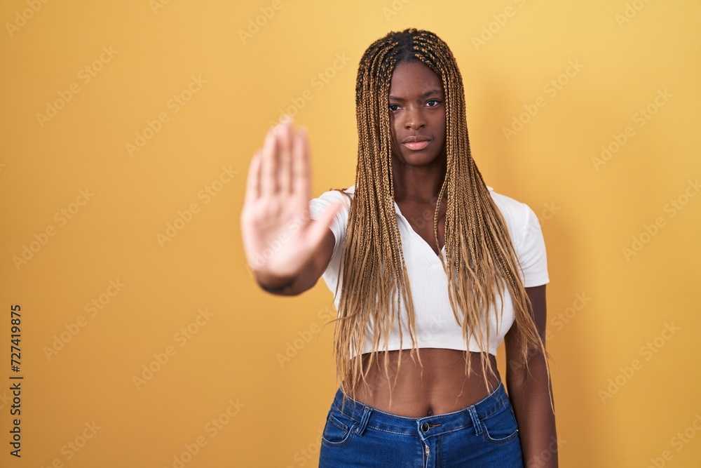African american woman with braided hair standing over yellow ...