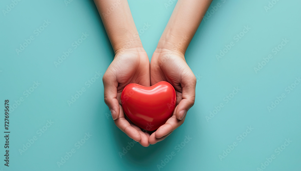 Hands clasping a red heart against a backdrop of blue Stock ...
