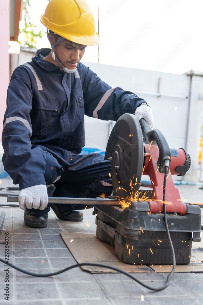 Asian worker wearing a safety suit uses a steel cutting (circular saw ...