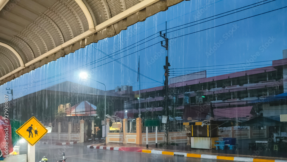 Raining on street in front of school in evening time, perspective side ...