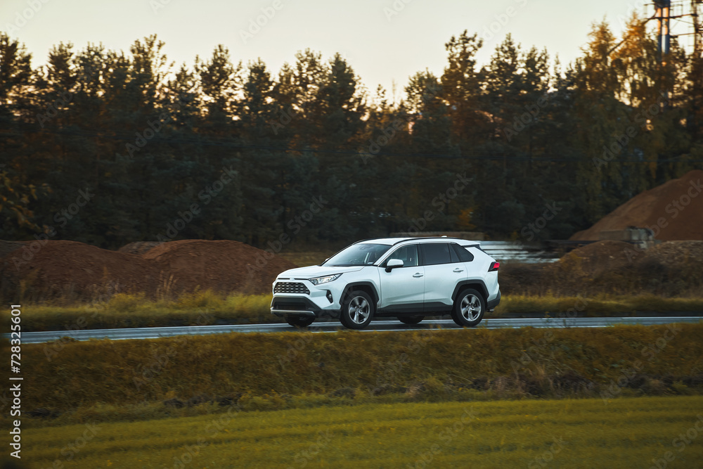 A modern family SUV car journeys along a scenic road with majestic ...