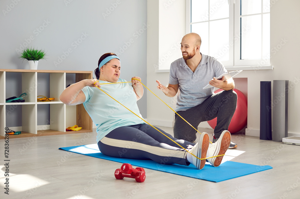 Overweight woman doing fitness workout with her trainer in fitness club ...