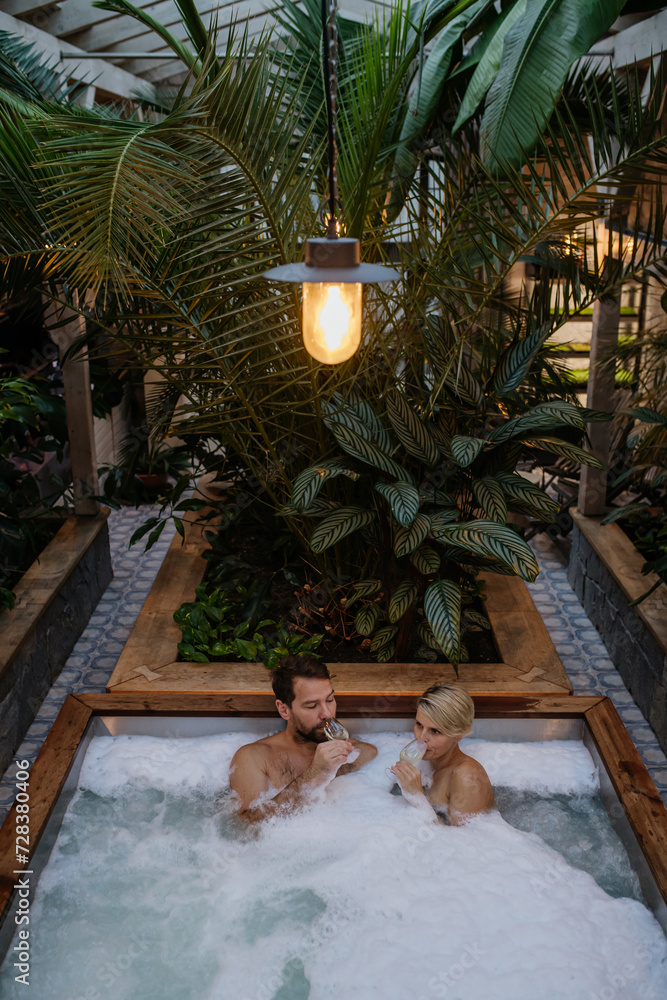 Beautiful mature couple relaxing in hot tub, drinking champagne ...